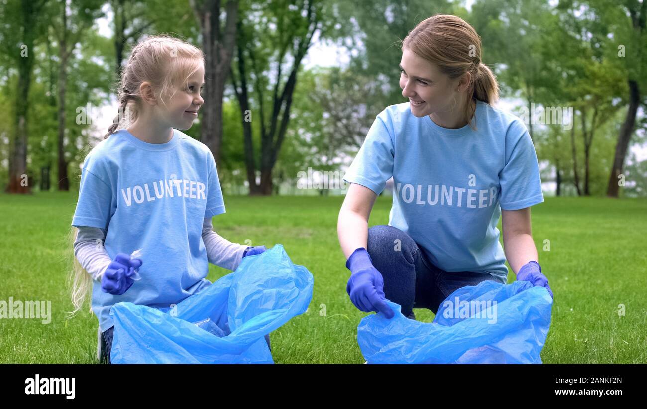 Caucasian woman with female child collecting garbage in park, smiling ...