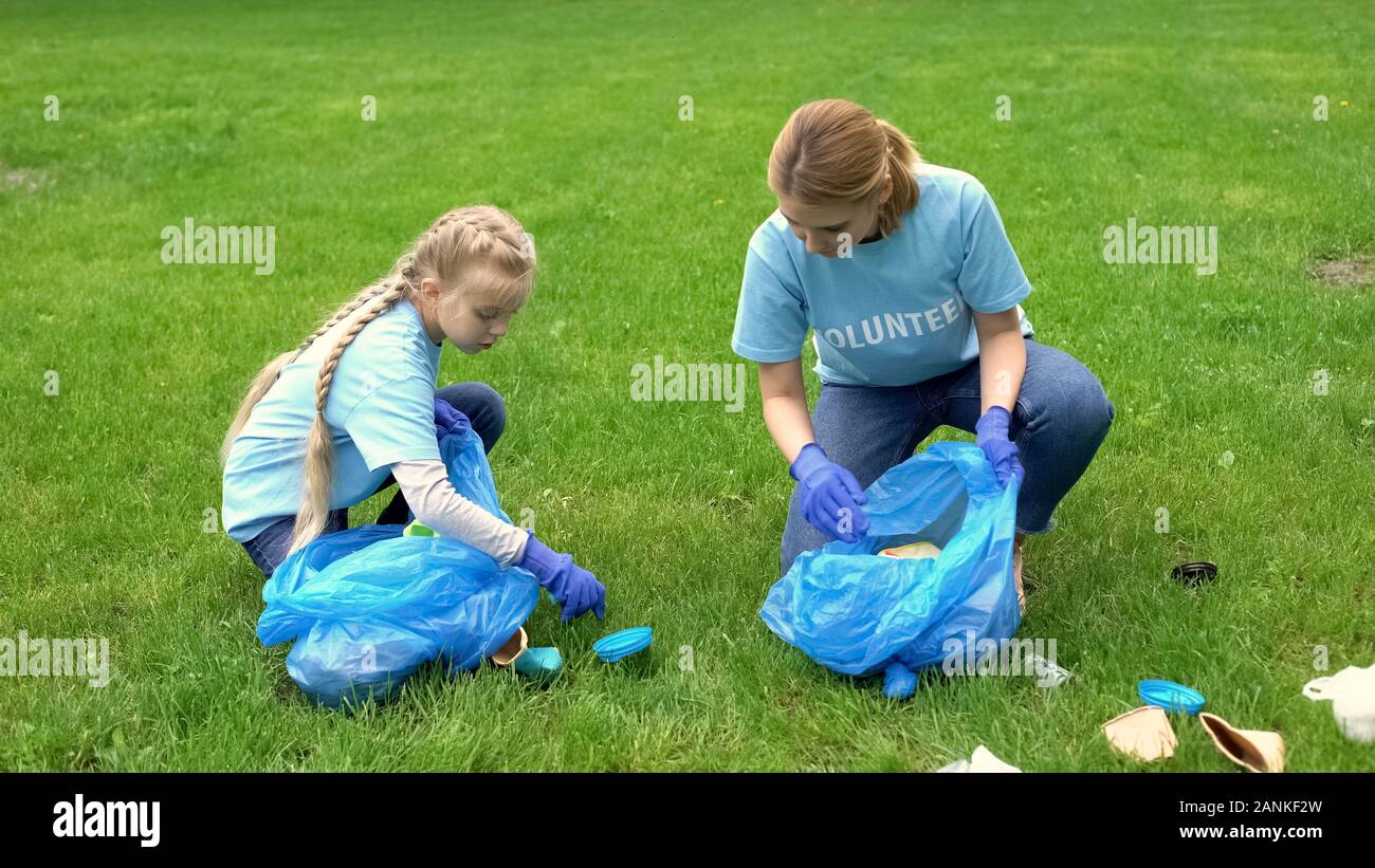 Schoolgirl and teacher putting plastic in garbage bag, social ...