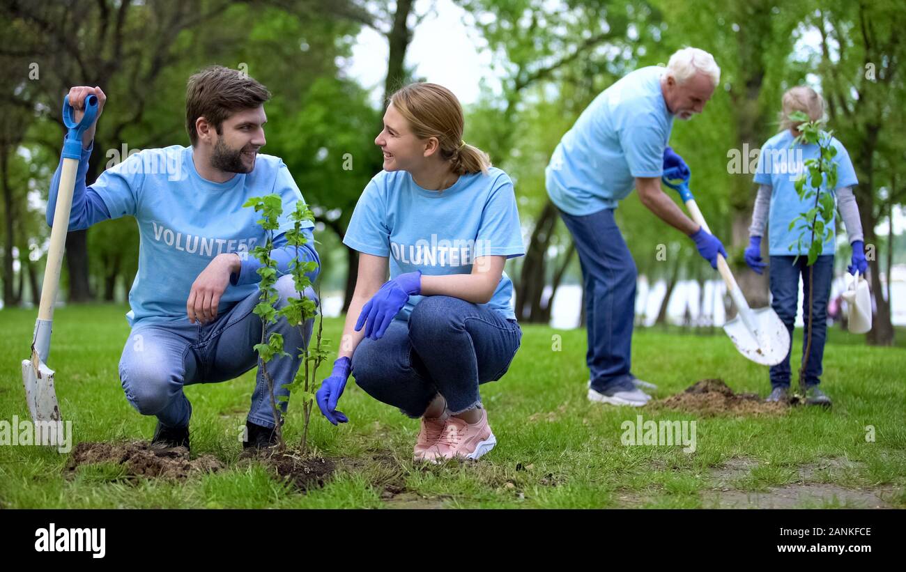 Group of eco volunteers planting tree sapling in public park, nature ...