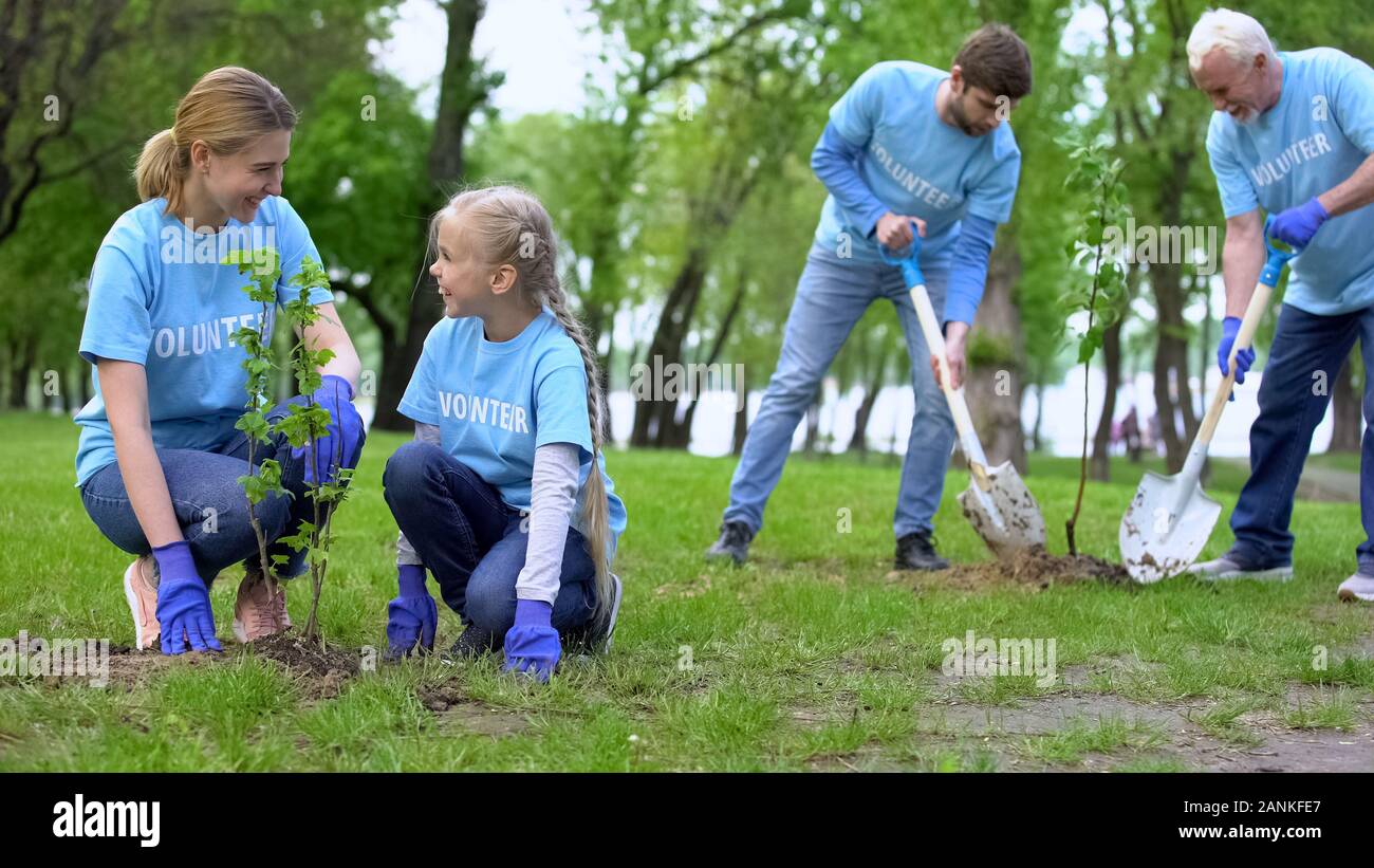Eco volunteers working at city park, planting trees, nature care and ...