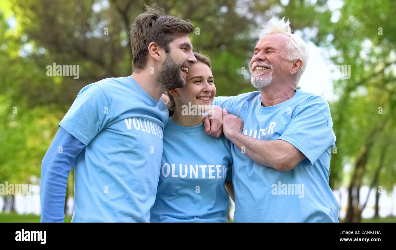 Happy volunteers hugging, enjoying nature care outdoors, teamwork ...