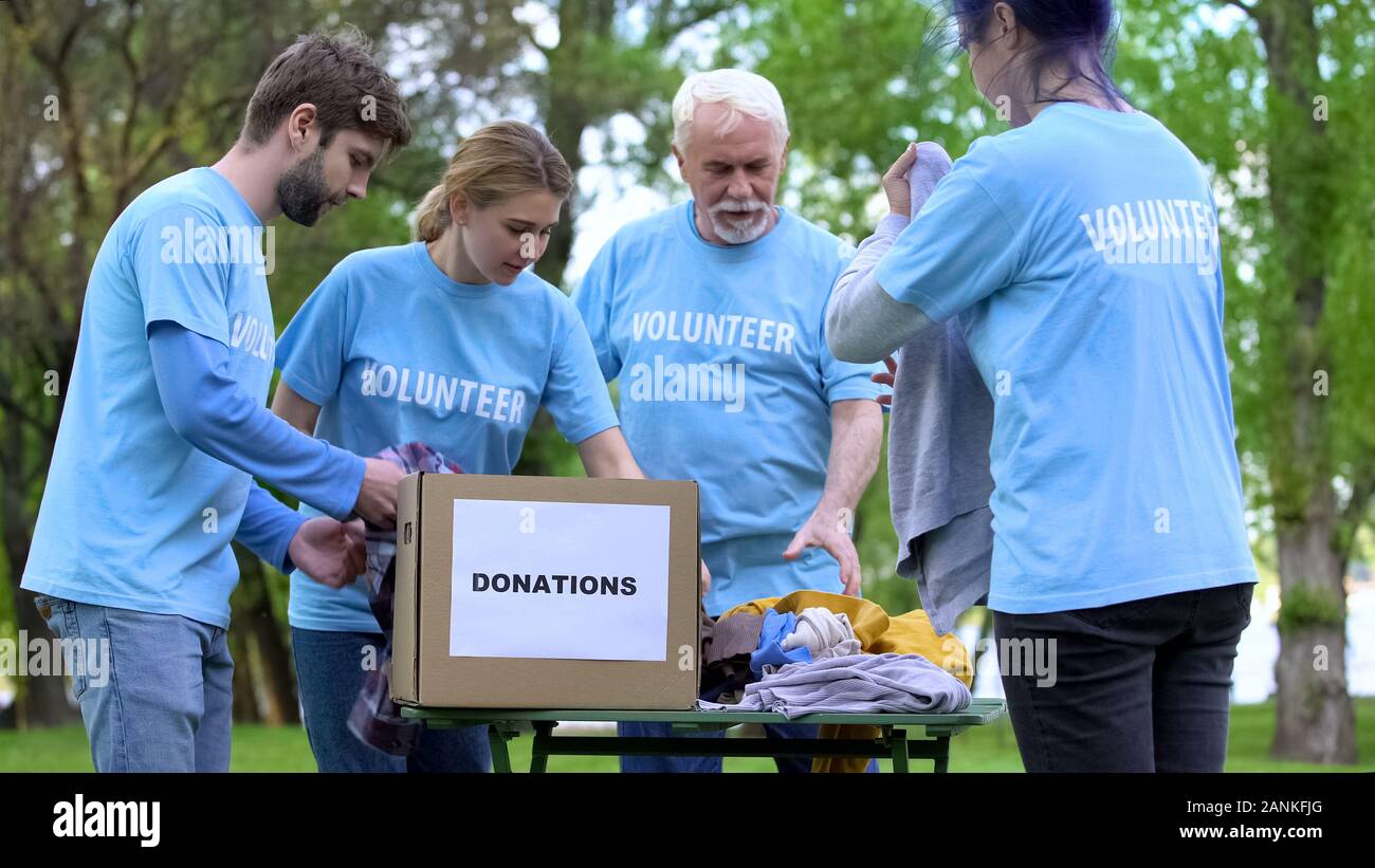 Volunteers sorting clothes putting in donation box, philanthropic ... Volunteers sorting clothes putting in donation box, philanthropic ...