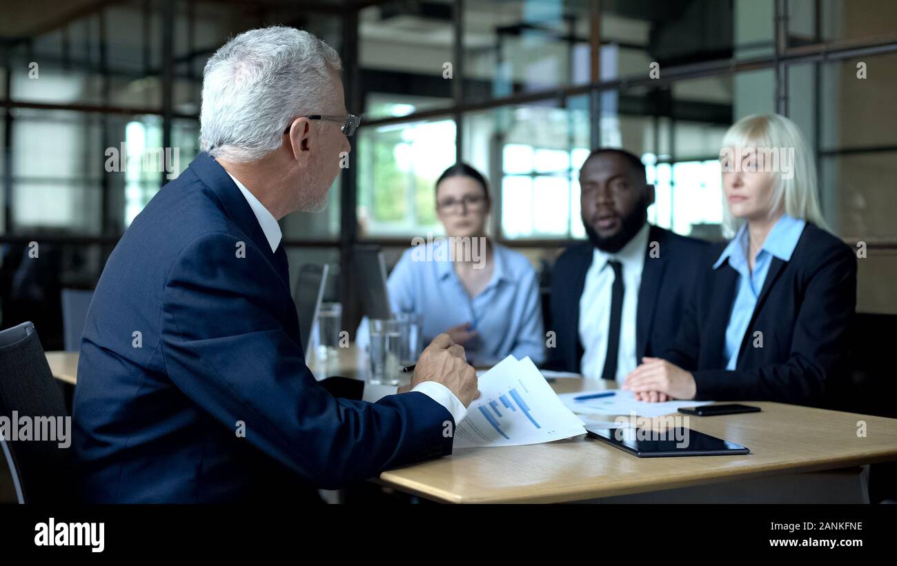 Serious director looking at company employees, discussing business ...