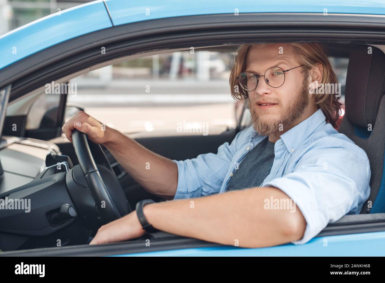 Transportation. Young bearded man in glasses traveling by electric car ...