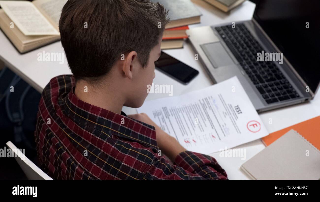 Sad school pupil looking negative test result upset bad mark, education ...