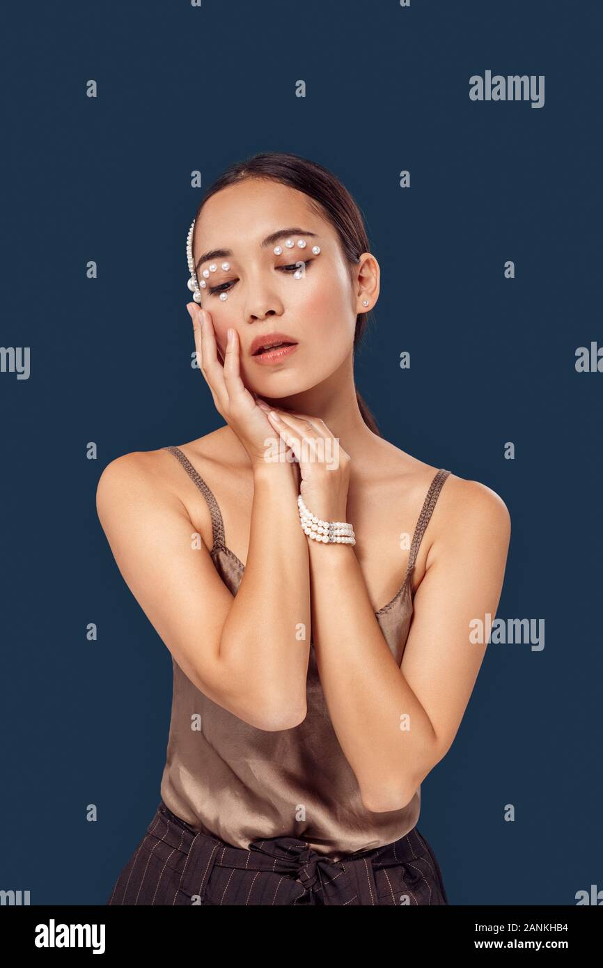 Freestyle. Young woman eyes decorated with perls standing isolated on ...