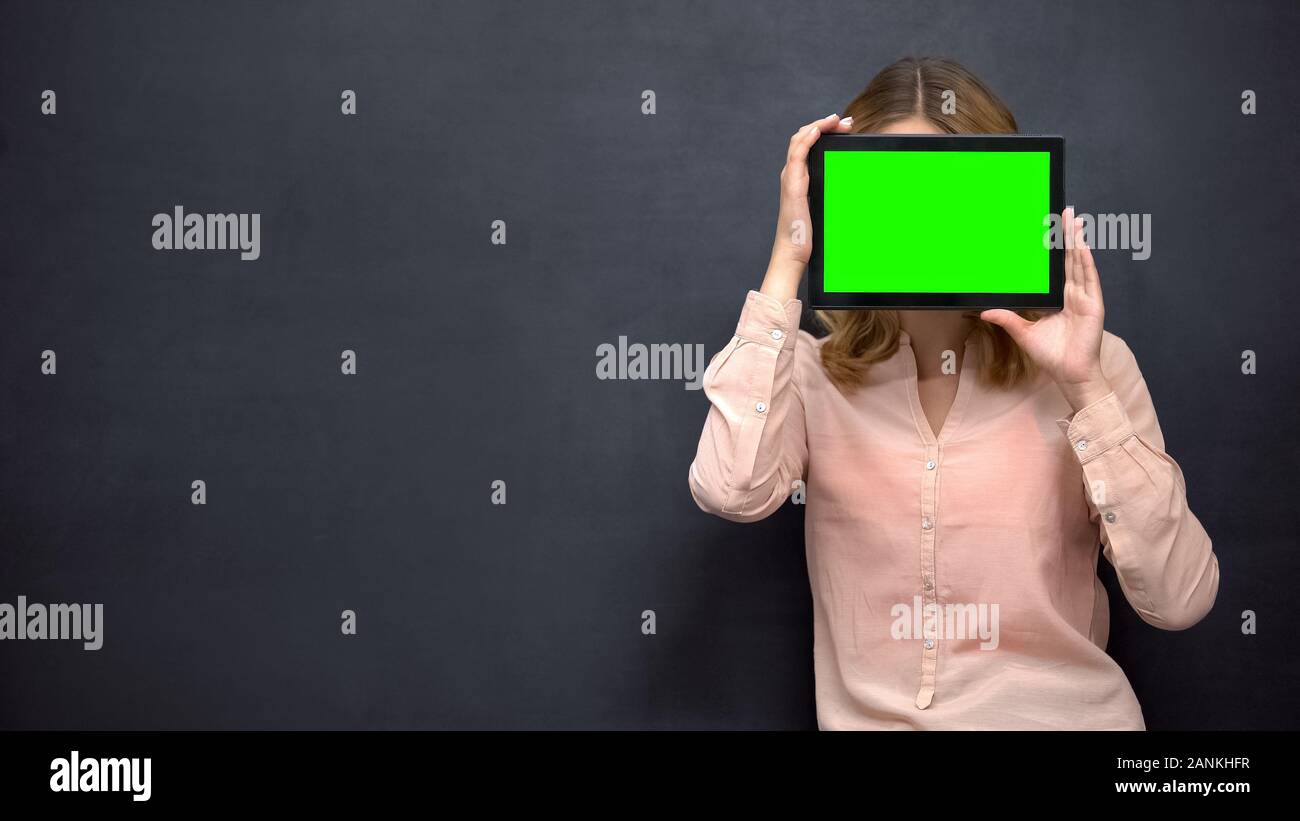 Girl hiding face behind green screen, concept of anonymity on internet ...