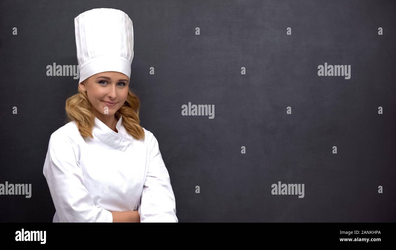 Positive chef looking at camera against black background, high-end ...