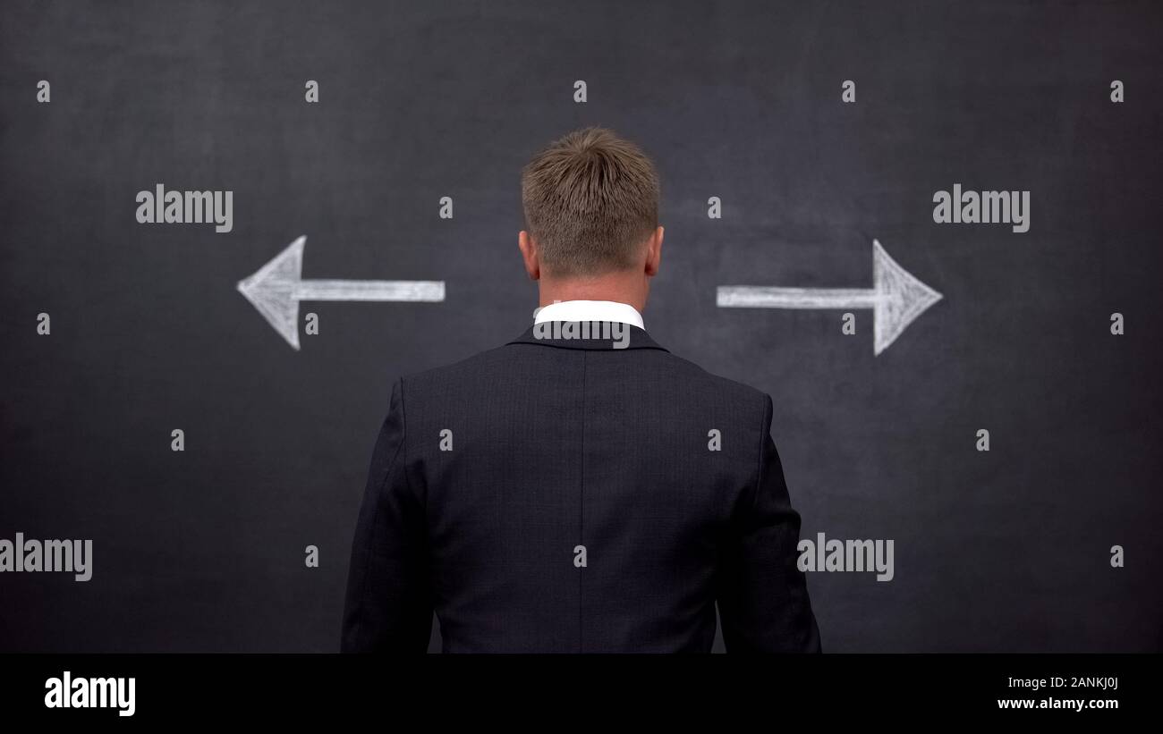 Businessman Standing Between Arrows Showing Different Directions Back