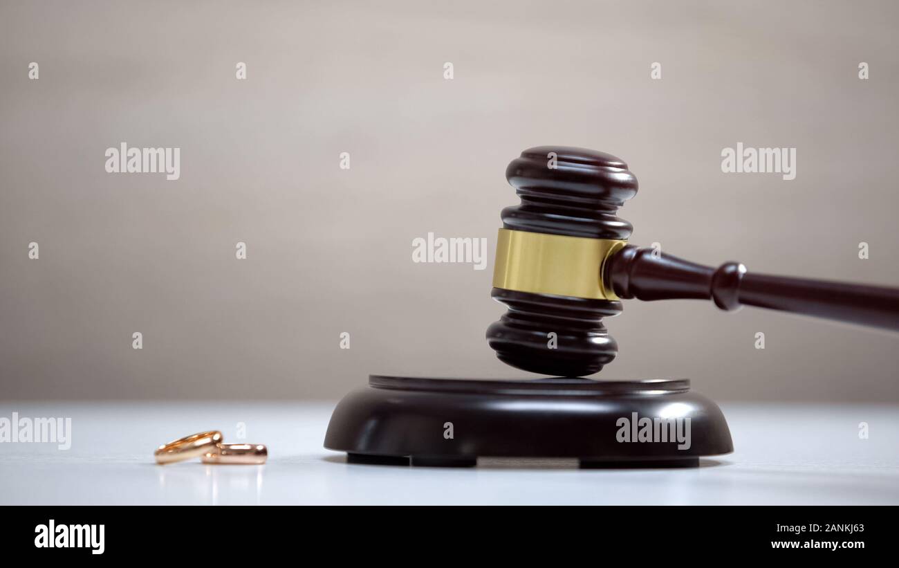 Wedding rings on table, gavel standing on sound block, divorce ...