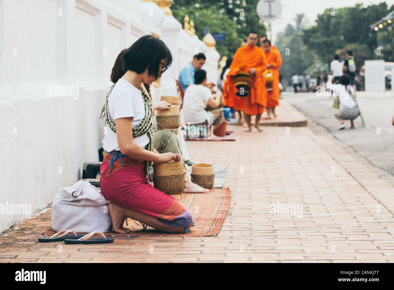 Luang Prabang, Laos - May 2019: Laotian woman making offerings to ...