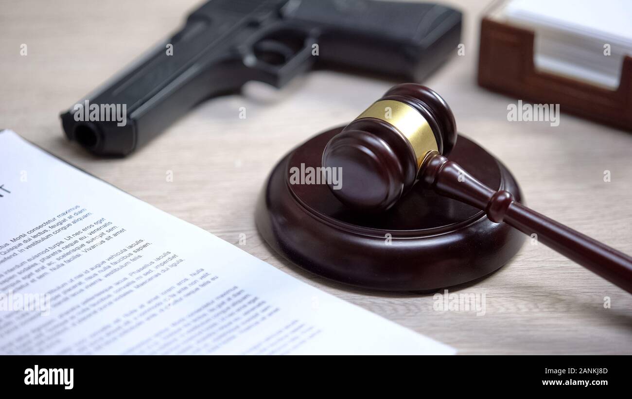 Gun on table, gavel lying on sound block, illegal use weapon, court ...