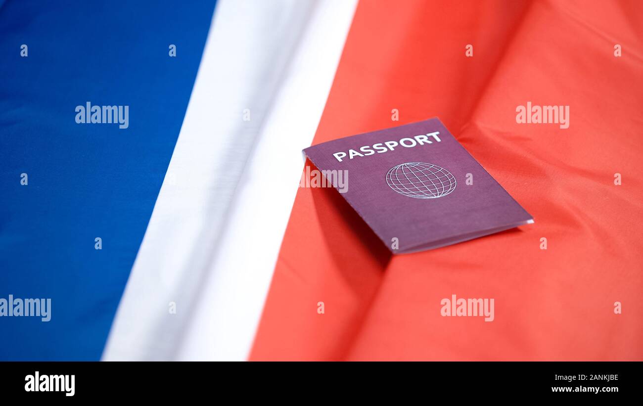 Female hand putting international red passport on french flag ...