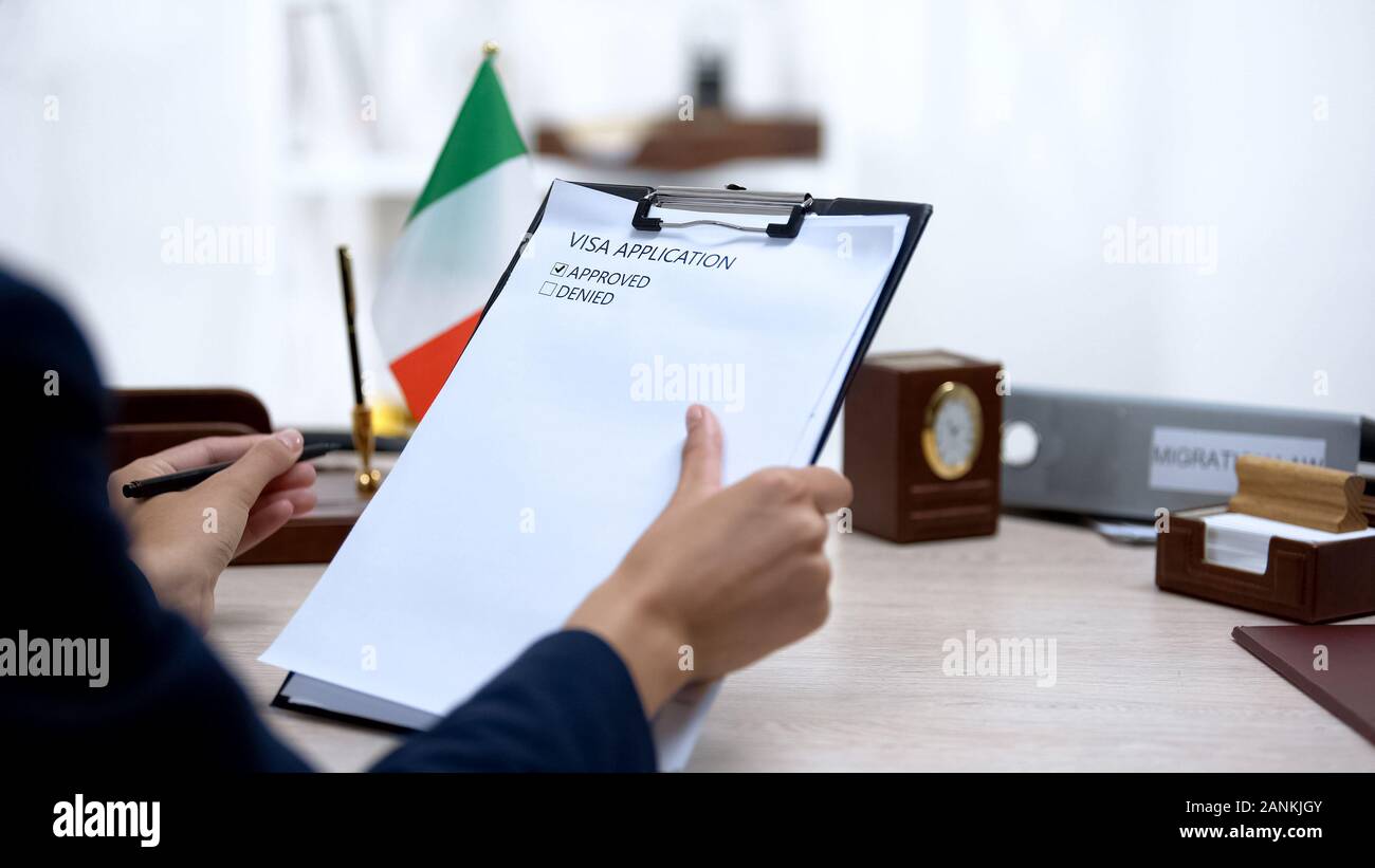 Embassy employee approving visa application, italian flag on table ...