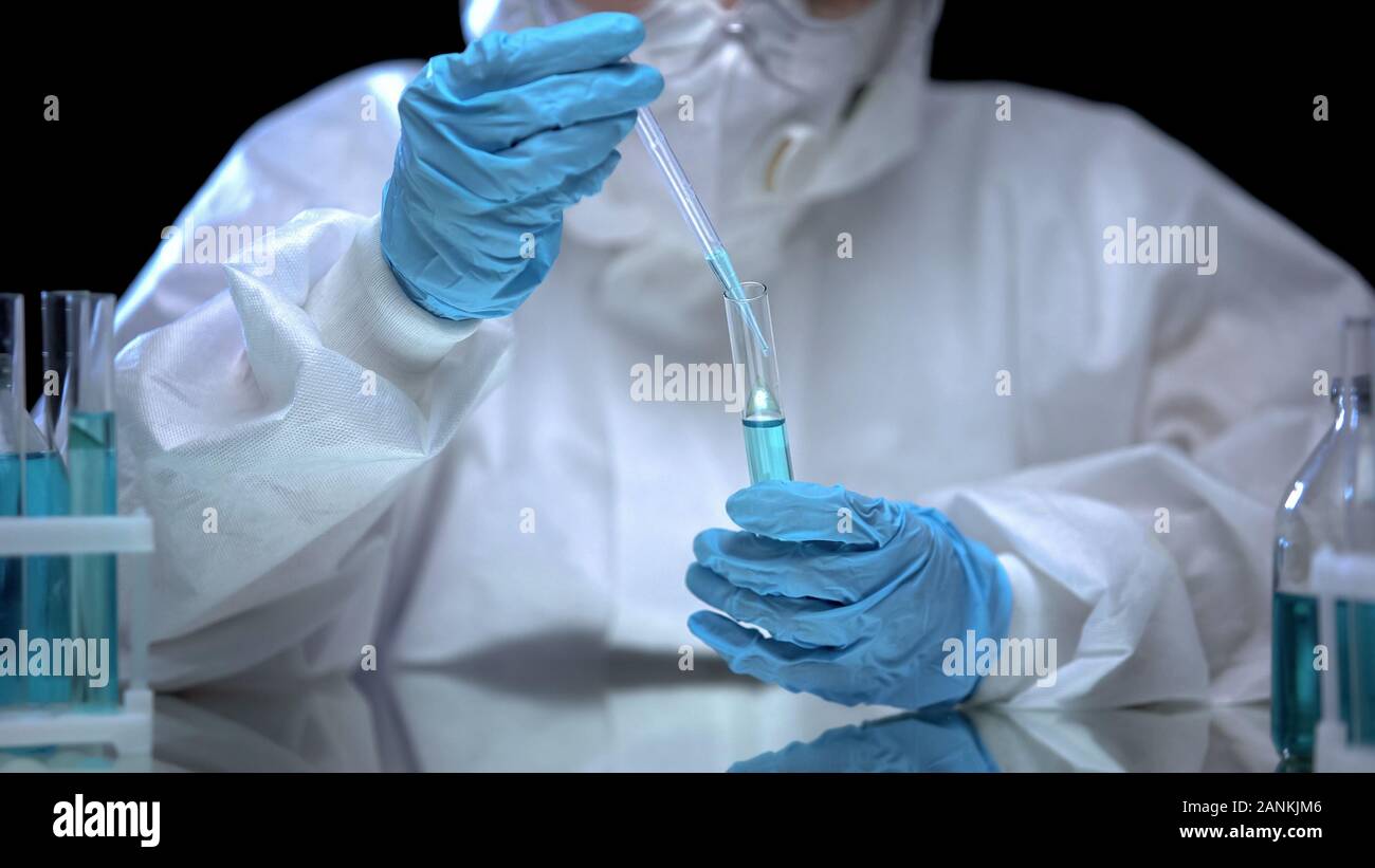 Chemistry lab assistant taking sample of blue liquid from test tube ...