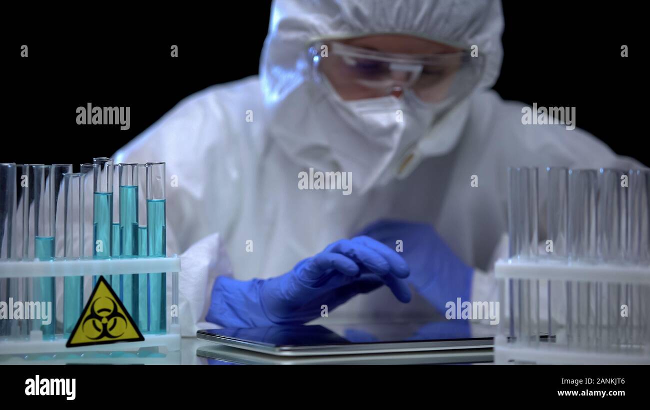 Female toxic lab worker making notes on tablet analyzing biohazard ...