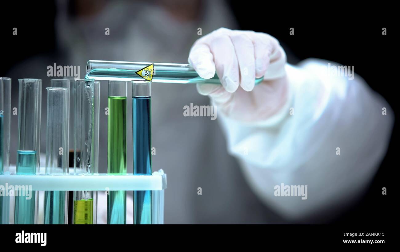 Laboratory worker adding liquid from test tube with poison symbol, life ...