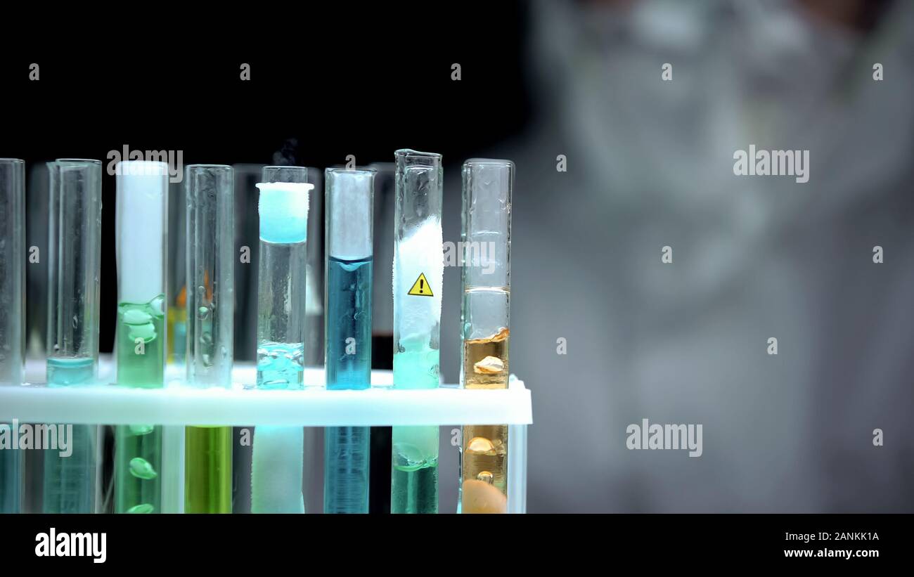 Researcher looking at test tubes with colorful liquids in lab, warning ...