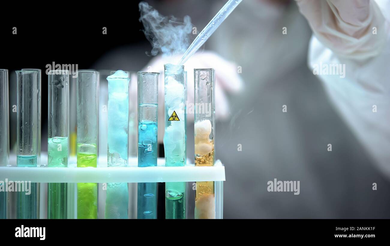 Lab worker pouring liquid in test tube with biohazard symbol, modern ...