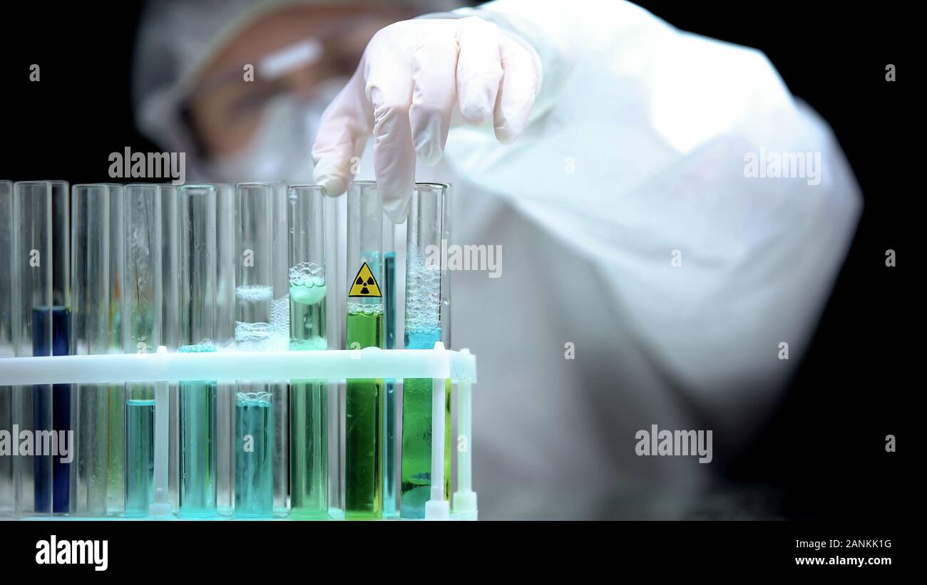 Lab worker taking test tube with green radioactive sample, ecological ...