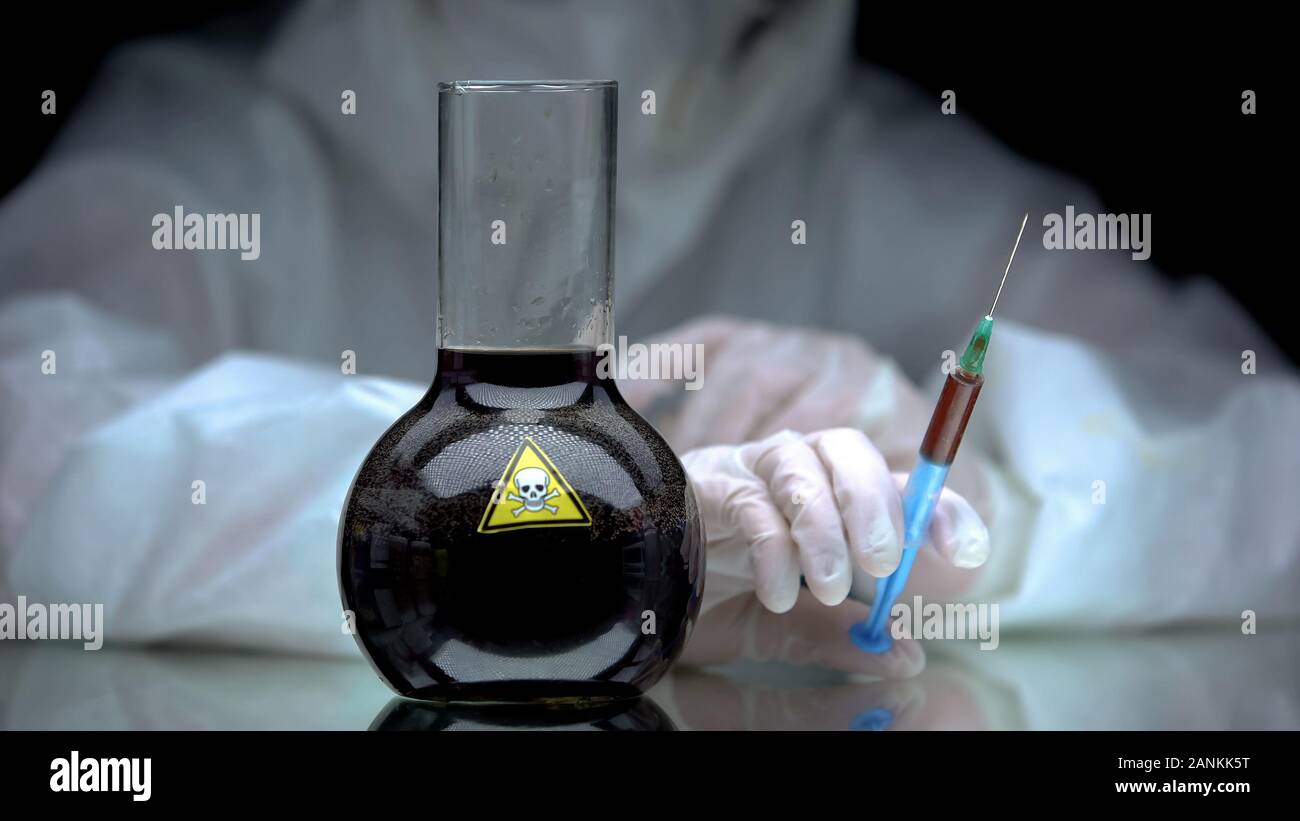 Laboratory worker holding syringe with poison, biochemical analyze ...