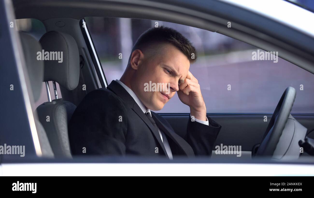 Upset man sitting in car, thinking over problems, stressful life ...