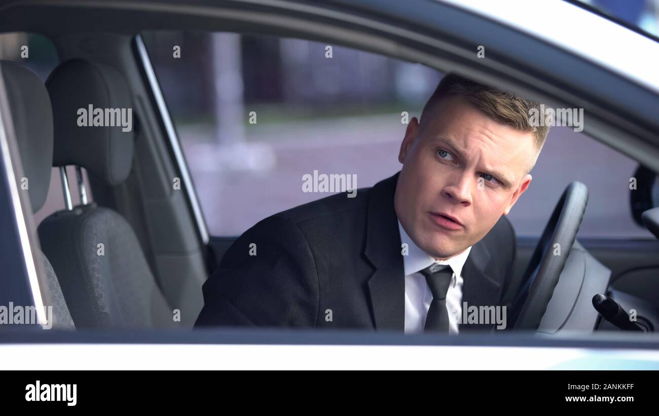 Irritated male driver looking out of car window, annoying traffic jam ...