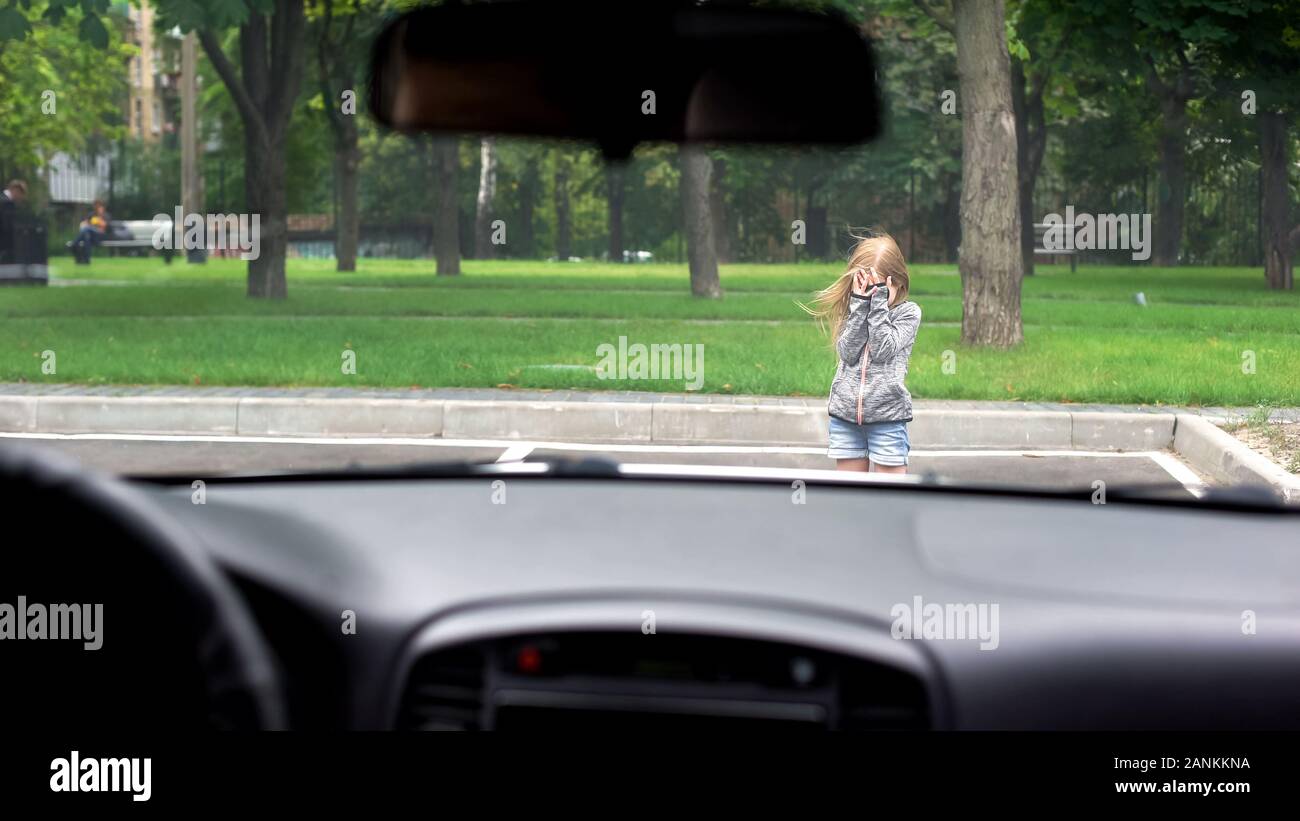 Scared little girl covering face, terrified by driving car, road safety ...