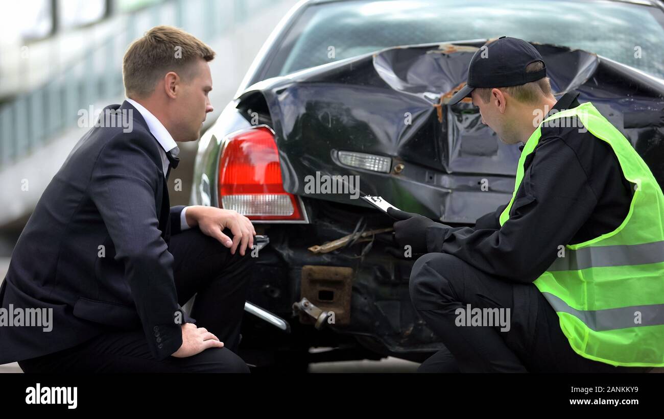 Police inspector filling car accident report analyzing damage, stressed ...
