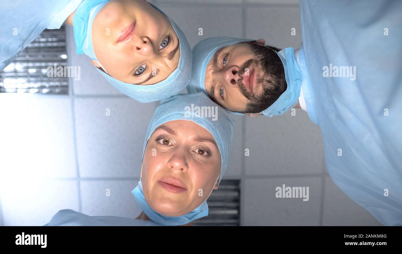 Serious surgeon team faces looking at patient waking up after coma ...