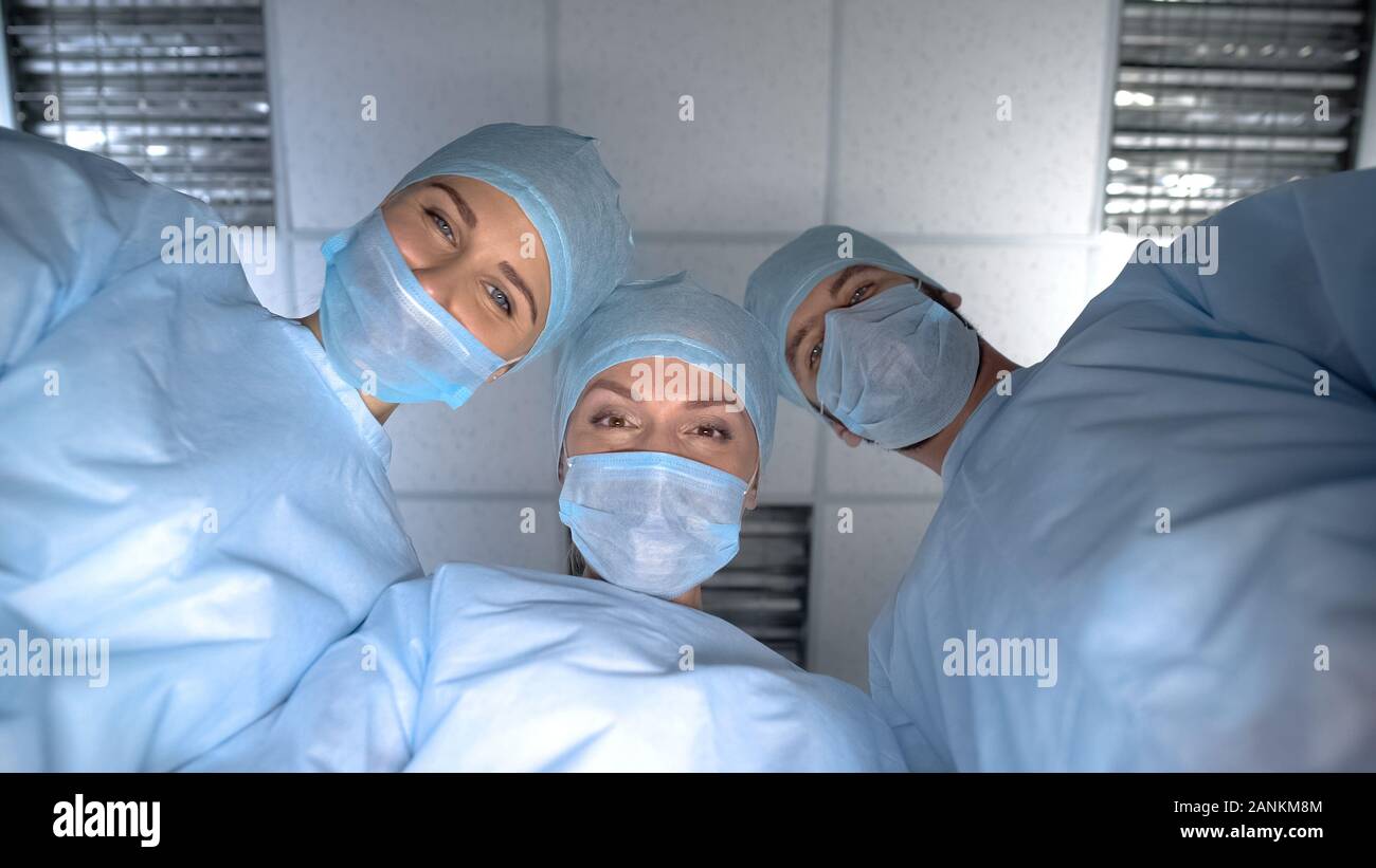 Pov patient waking up after operation anesthesia, smiling surgeon team ...