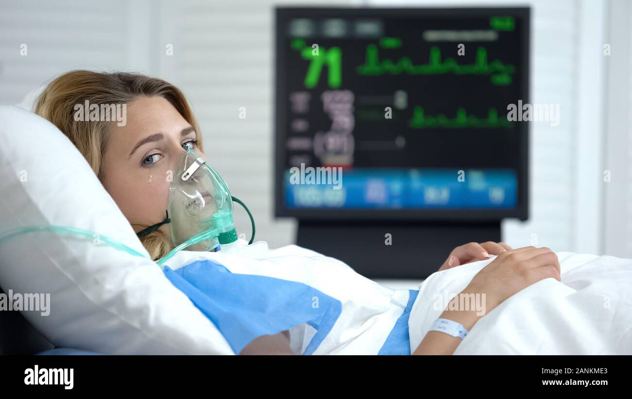 Crying woman in oxygen mask looking at camera, stabilized after surgery ...