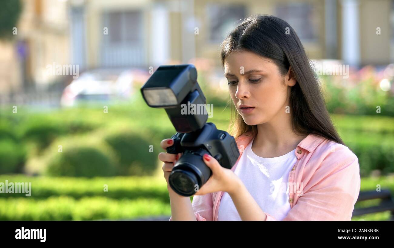 Serious female photographer checking settings on camera, technique ...