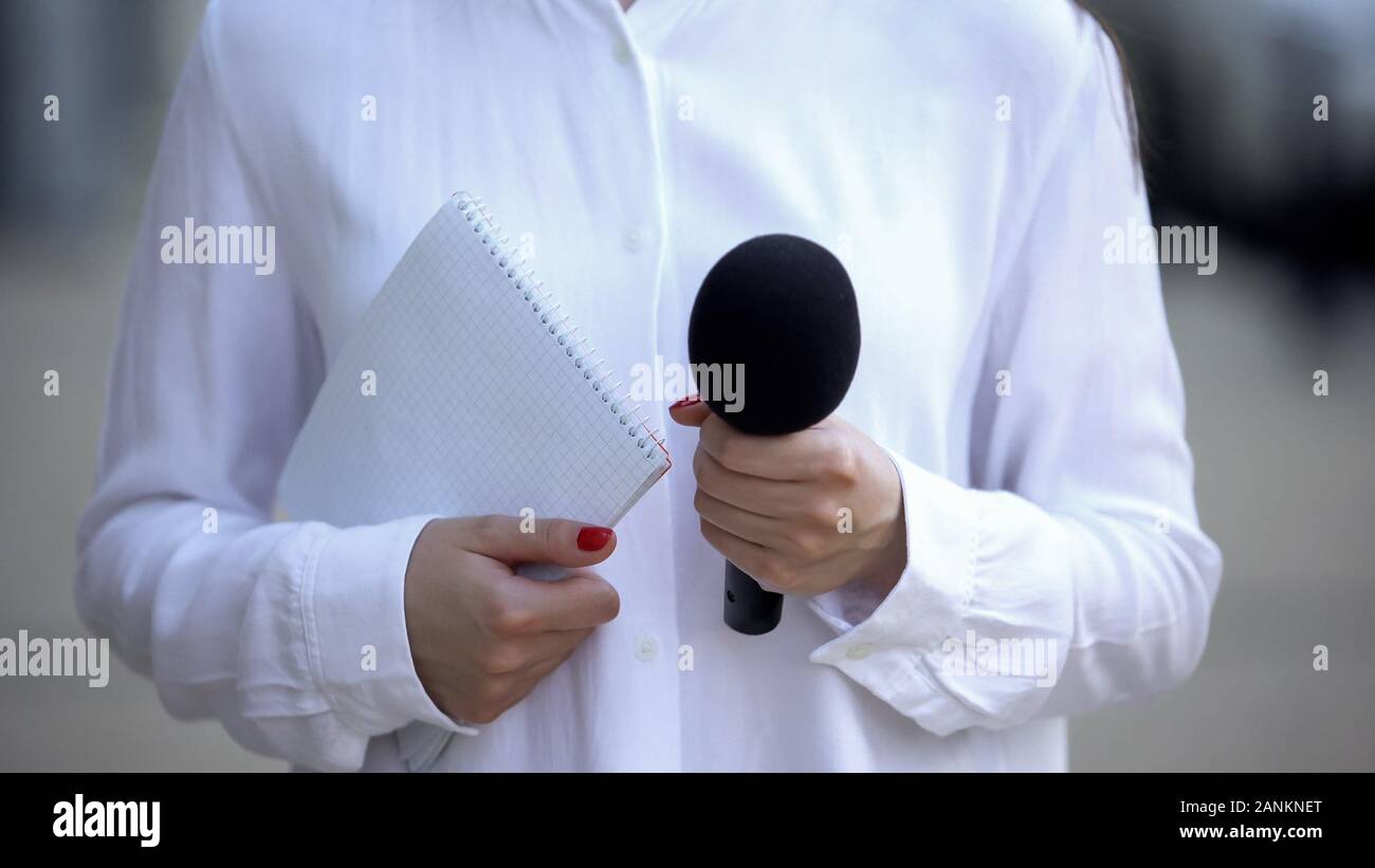 Female journalist holding notebook and microphone, preparing for ...