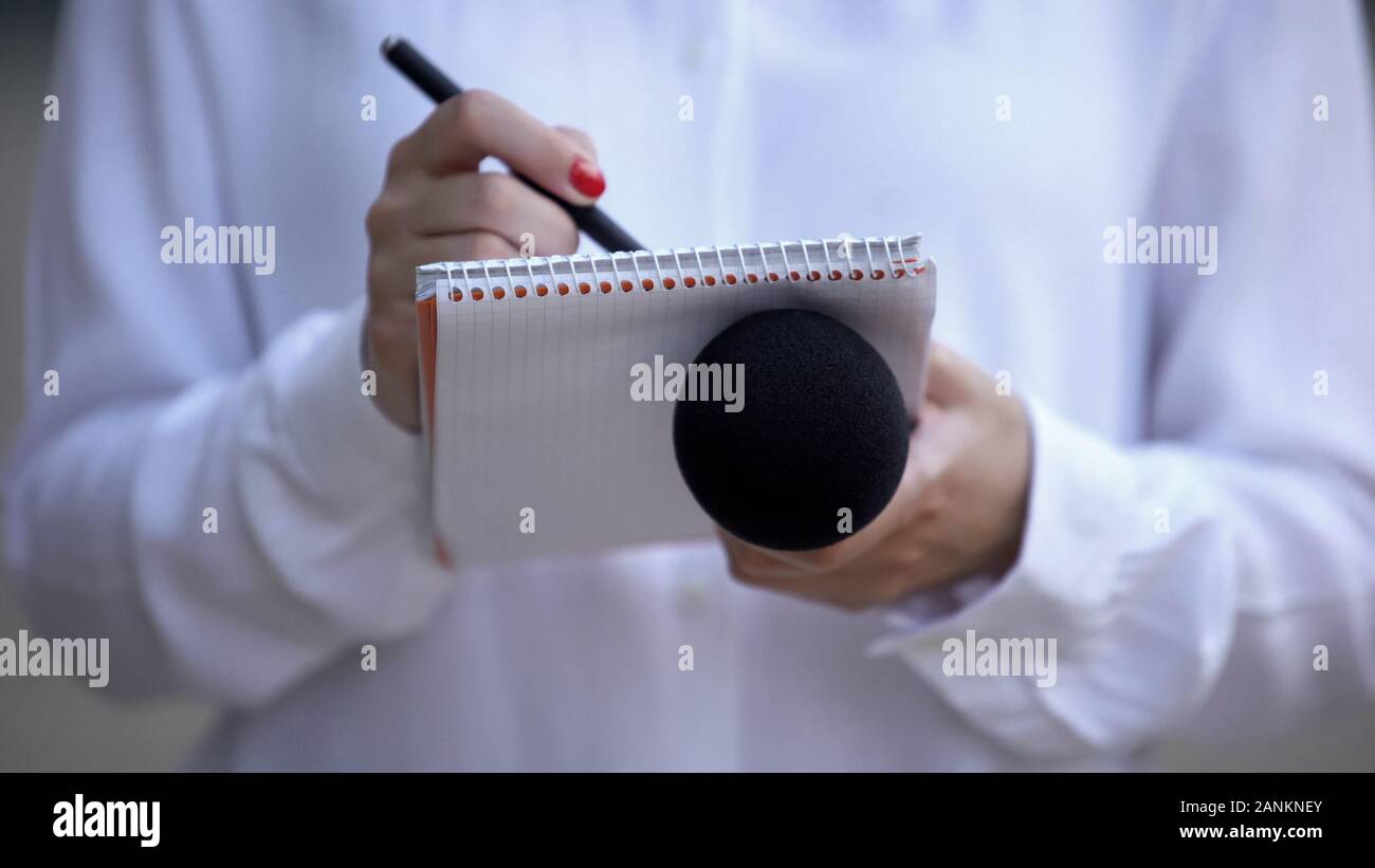 Journalist with microphone writing data in notebook, preparing ...