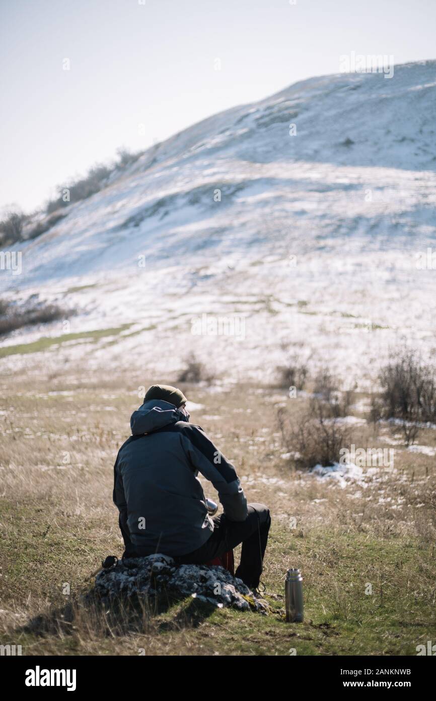 Back of a man sitting on a rock with snow mountain Stock Photo - Alamy