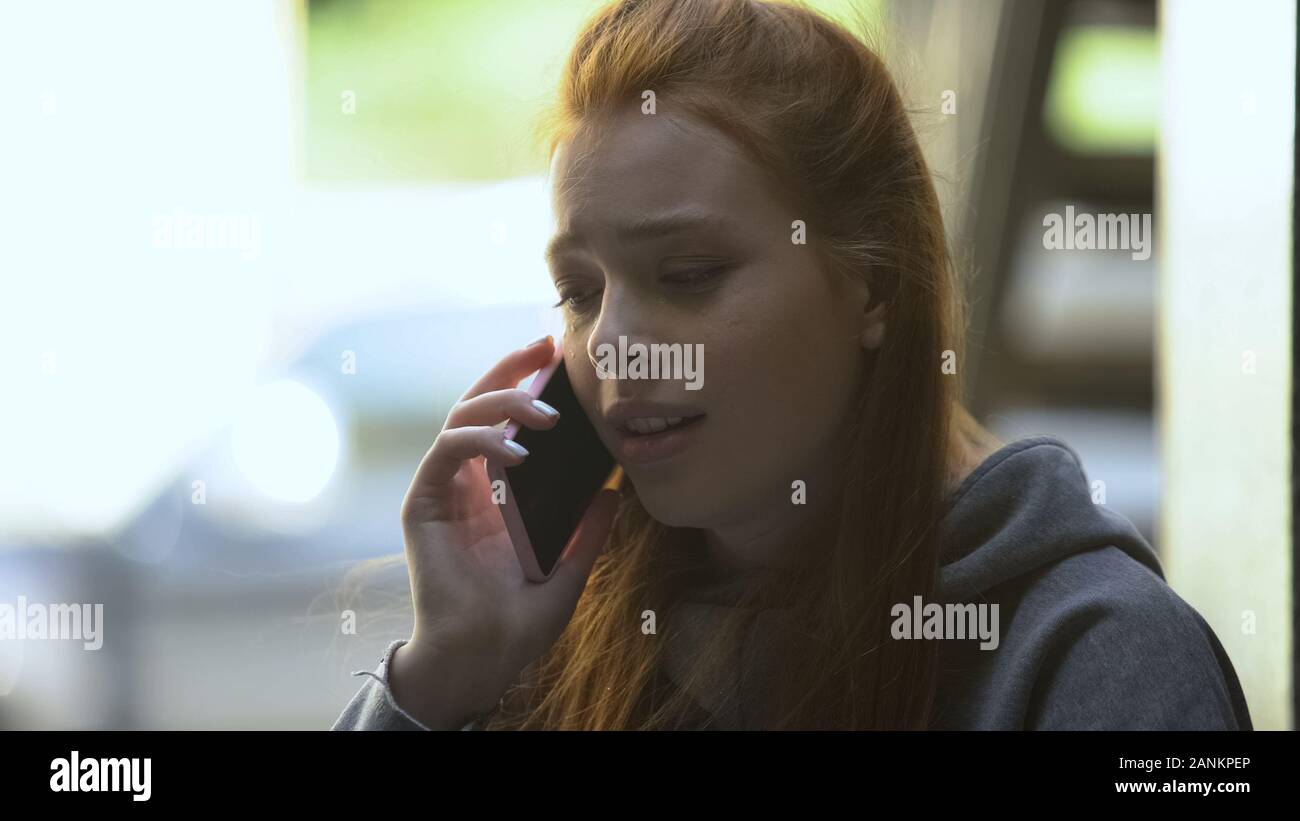Red-haired young female crying and talking on smartphone, needs help ...