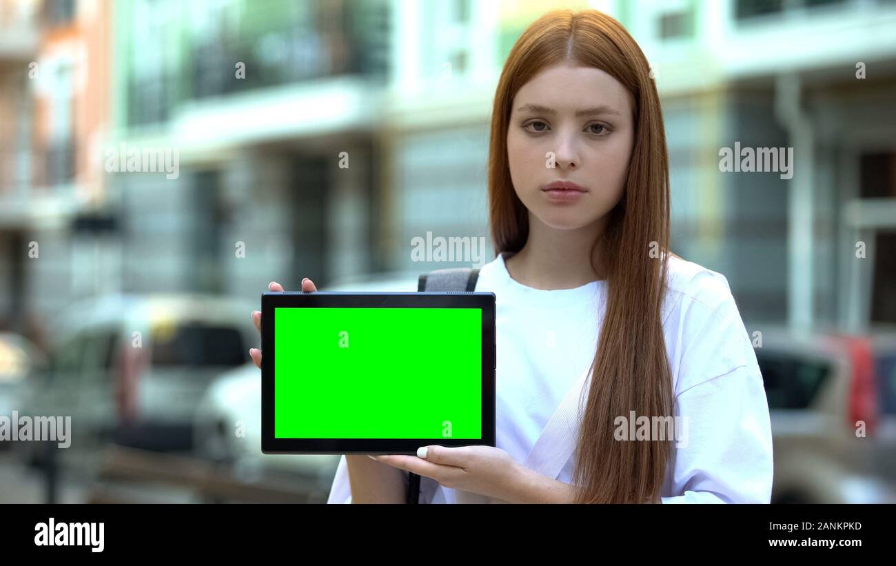 Serious girl holding green screen tablet, online courses, free trial ...