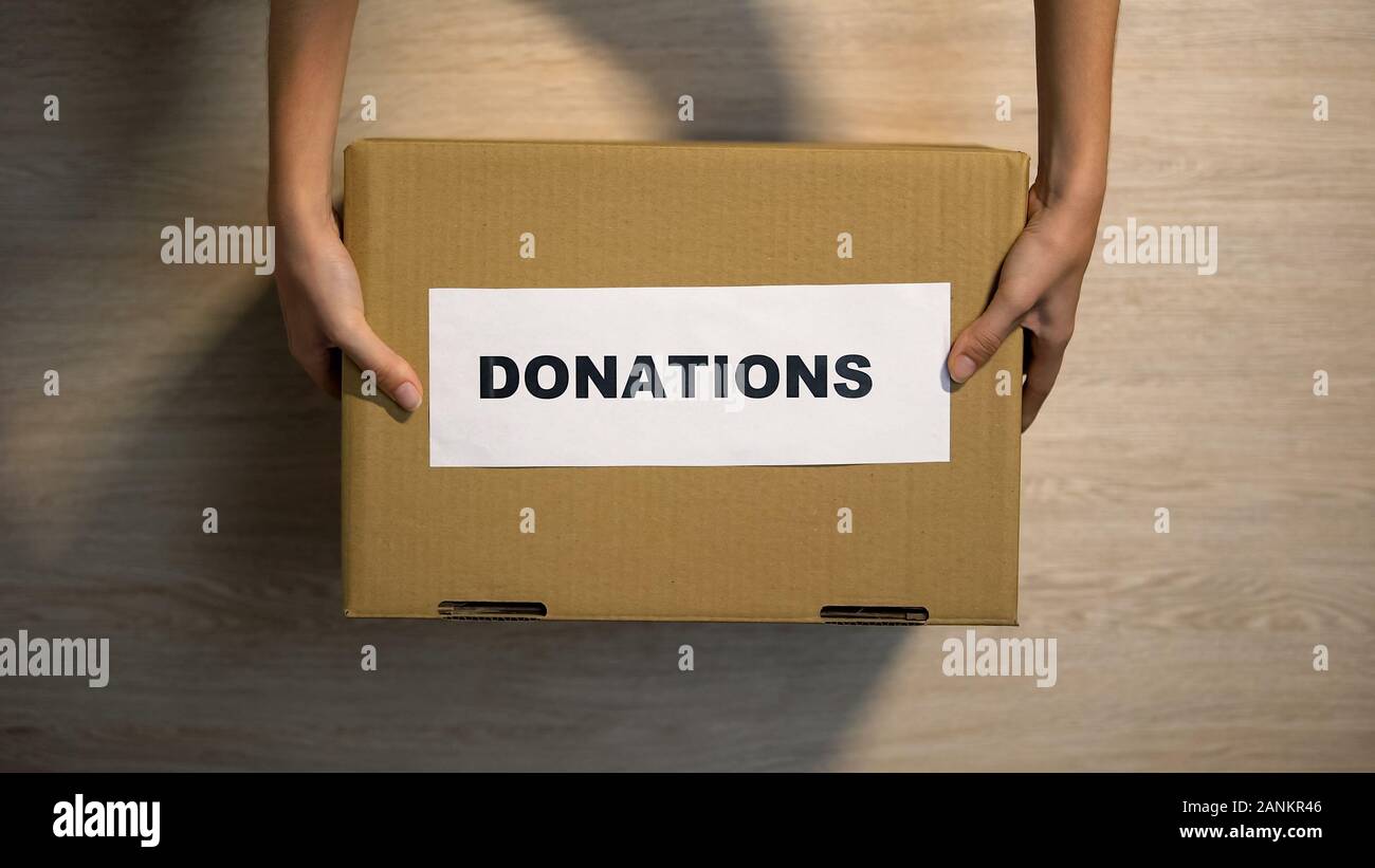 Volunteer holding cardboard box with donations, helping people in need ...