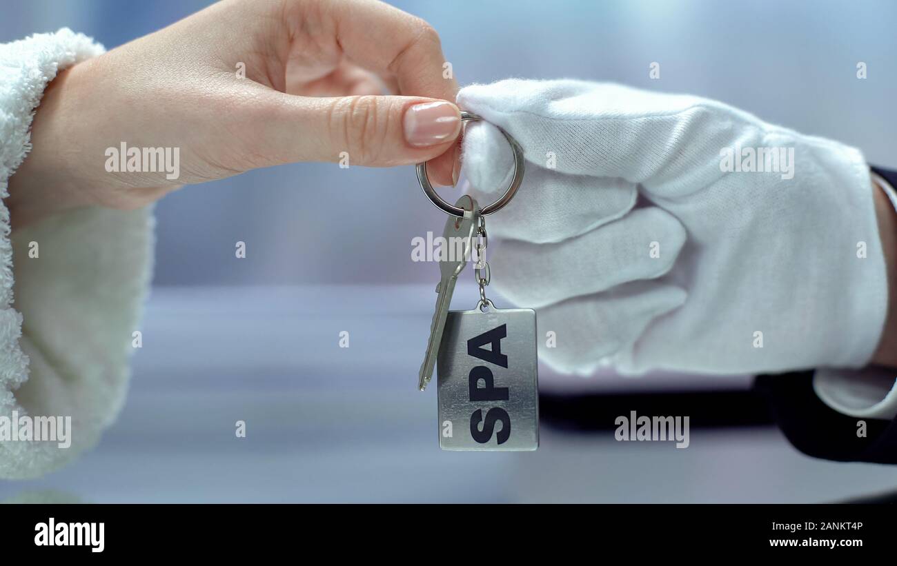 Lady taking SPA keys from receptionist in glove, relaxation in wellness ...