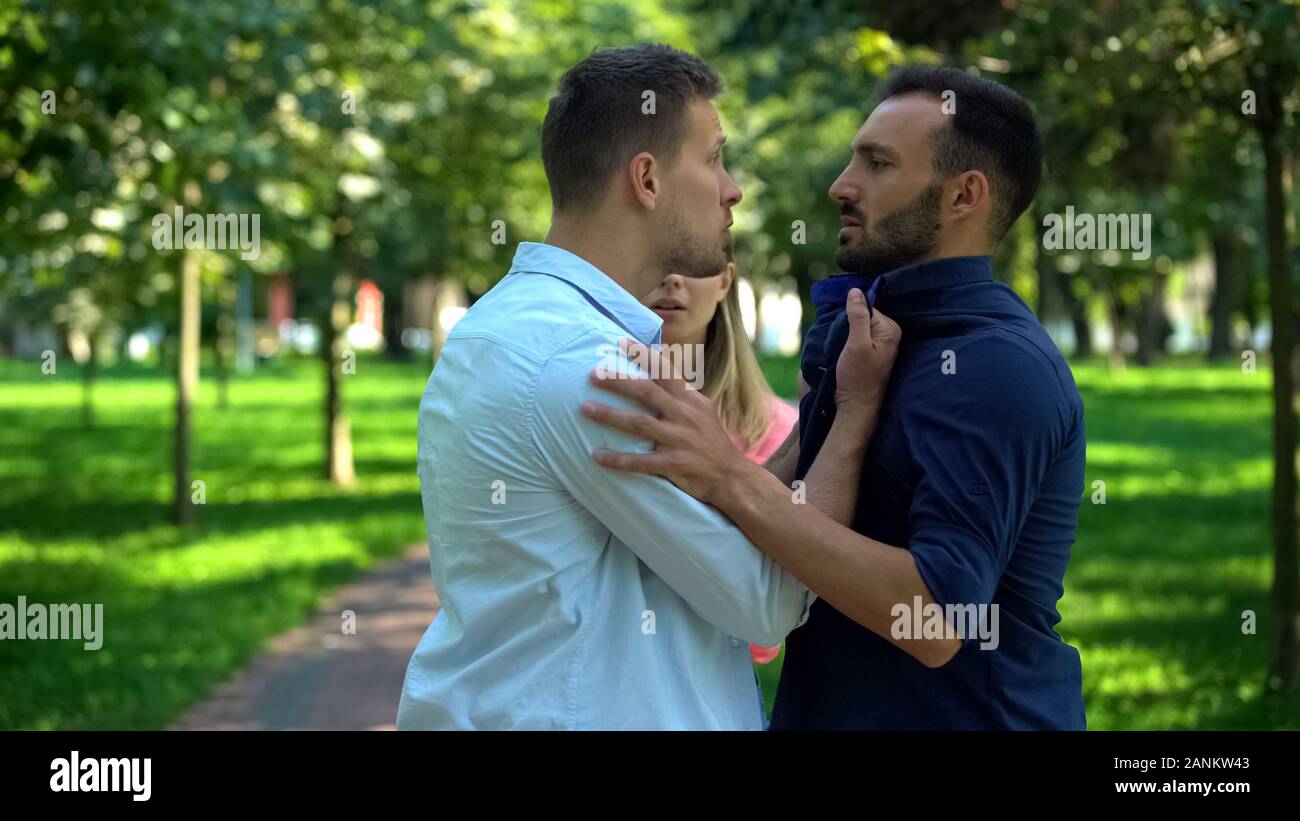 Aggressive men fighting outdoors, scared girlfriend trying calm down ...