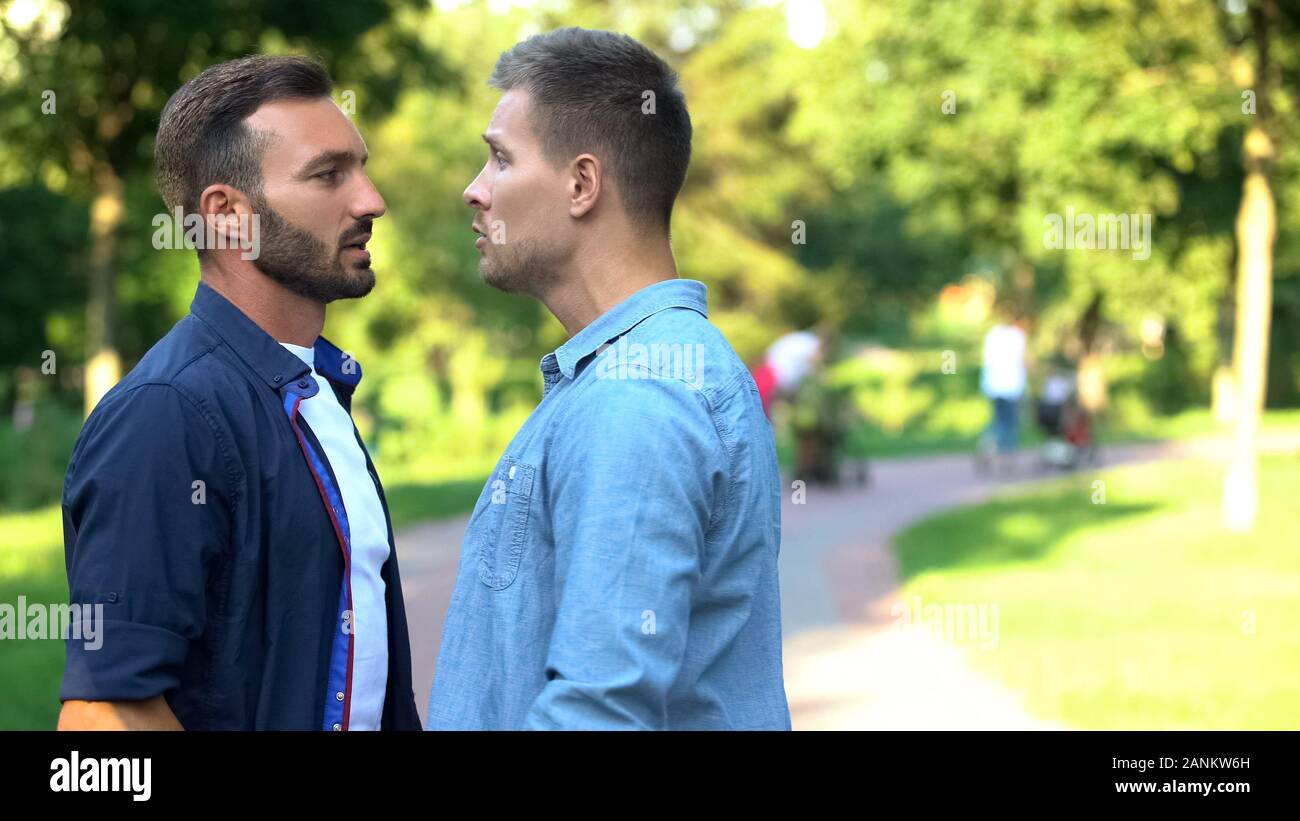 Aggressive young males looking each other outdoors, communication ...