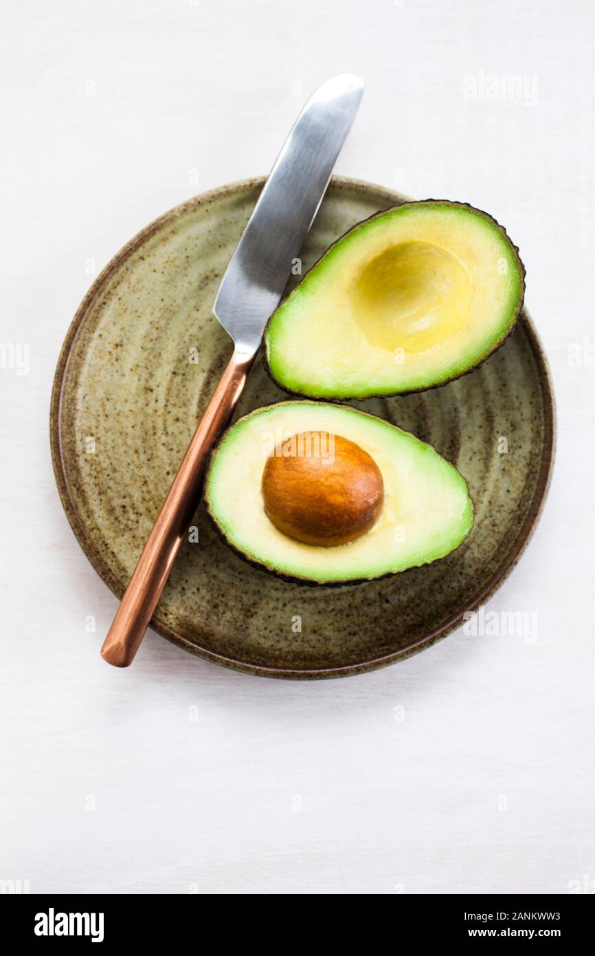 Avocado cut in half on a plate Stock Photo - Alamy