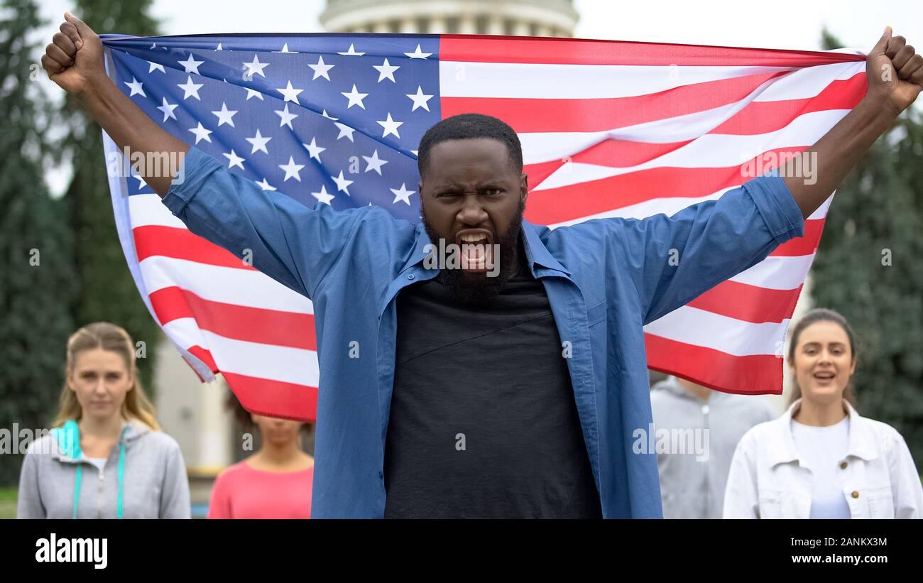 Irritated black man raising American flag, anti-racist rally, US ...