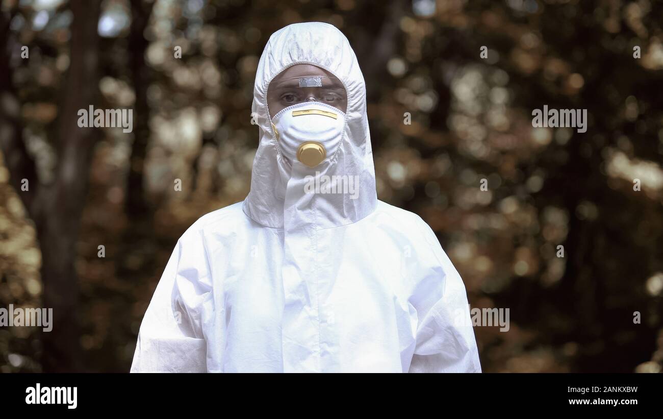 Woman in protective uniform and mask in forest exclusion zone ...