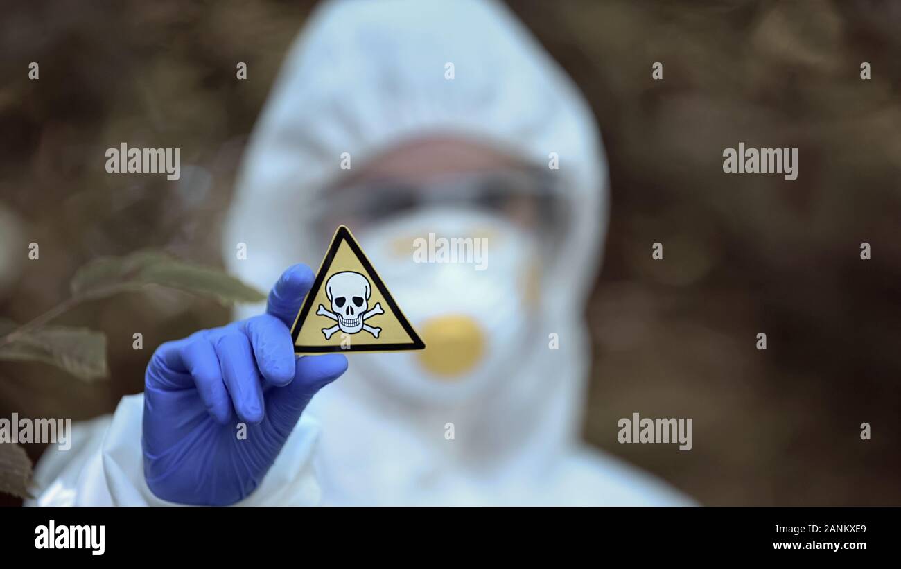 Female lab worker holding poison sign standing forest, dangerous level ...