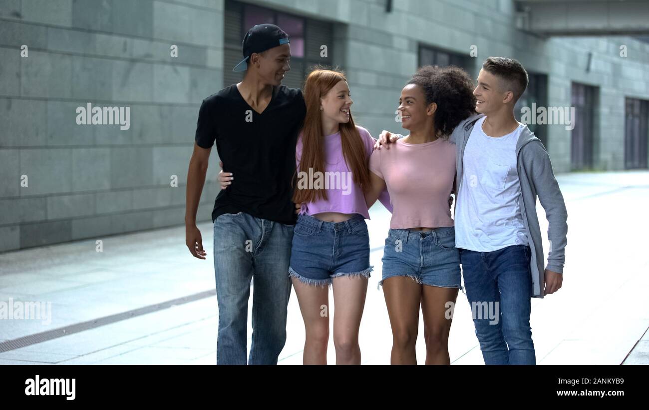 Positive group of young people hugging walking street, friendship ...