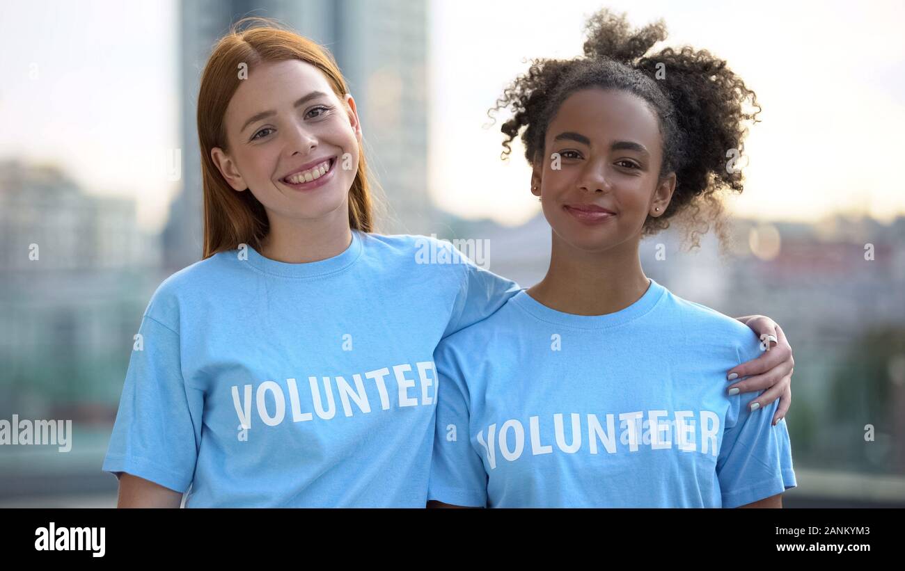 Two female volunteers smiling on camera, high school charity program ...