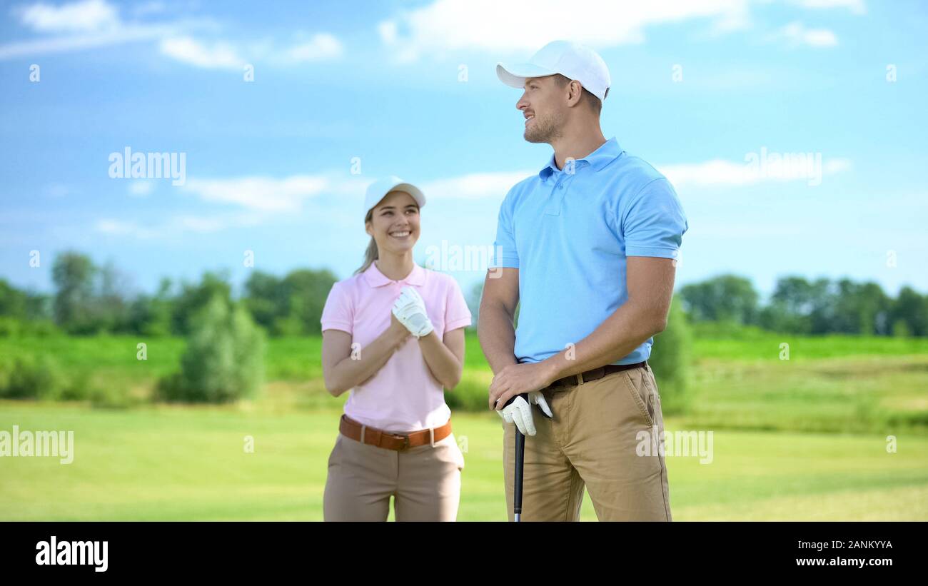 Female golfer rejoicing male partner golf game victory, successful shot ...