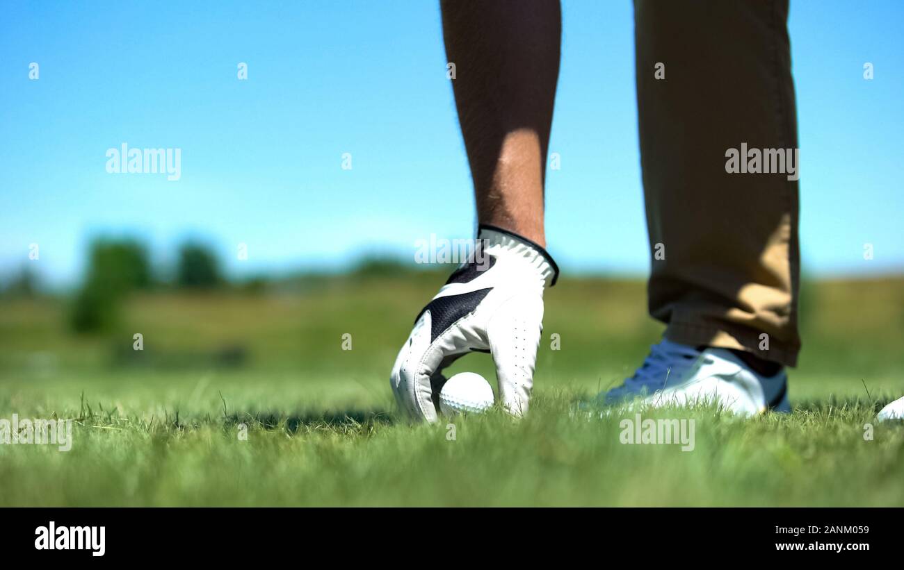 Male golfer teeing off golf ball before swing, professional and luxury ...